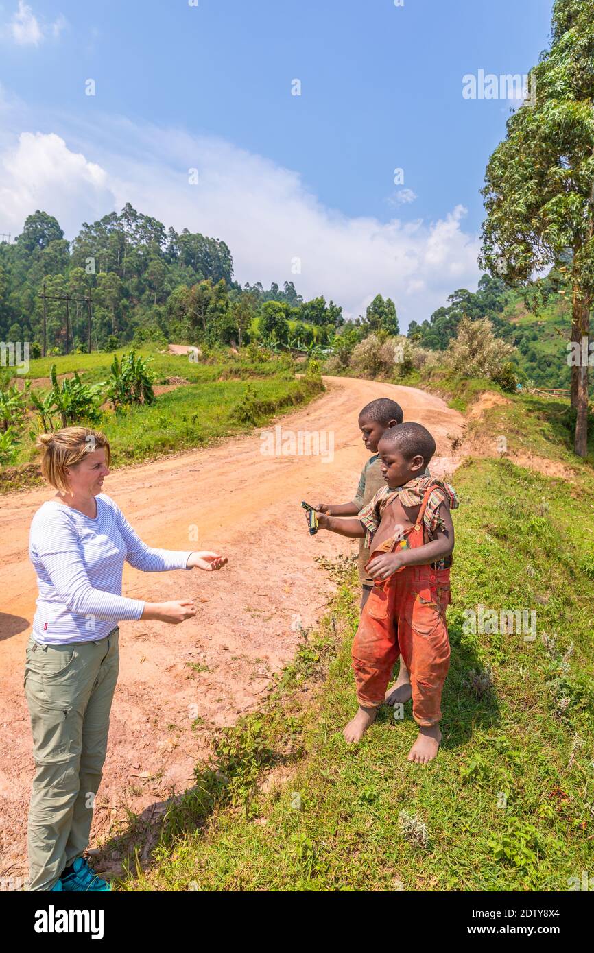 A tourist giving some kids in old ragged clothes in a rural area candy ...