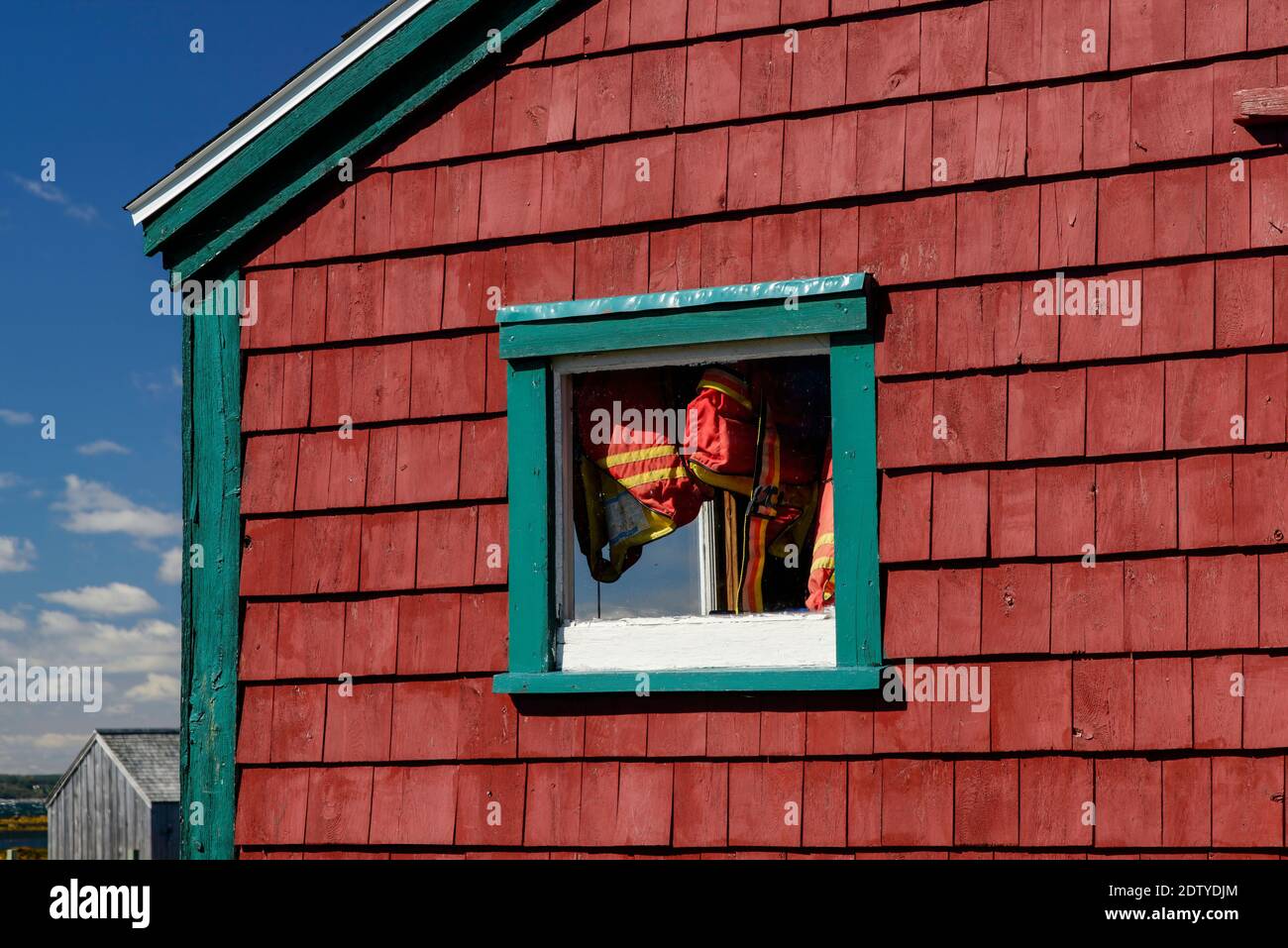 A green framed window in a red fishing shed displays orange life ...