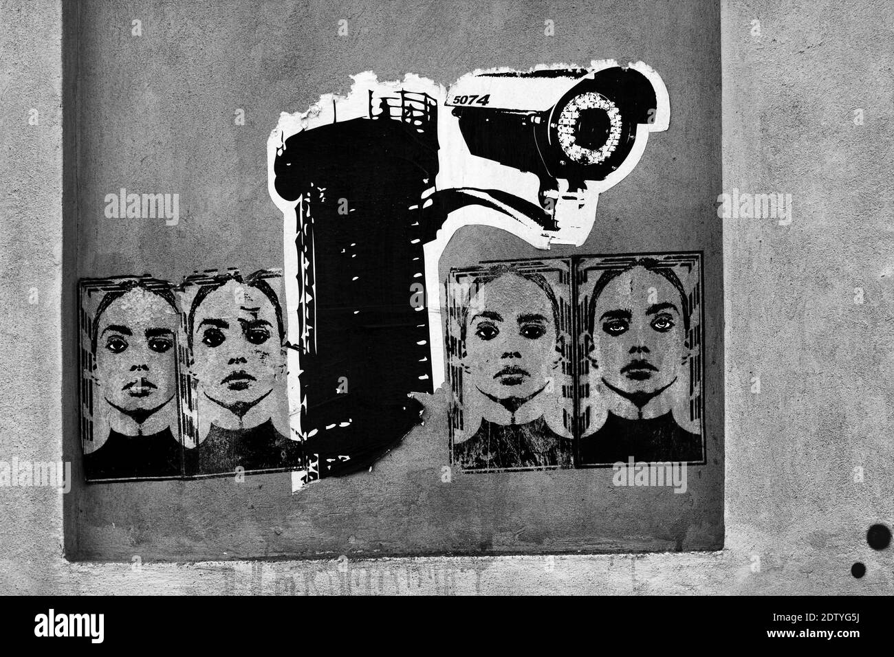 Graffiti cut outs pasted on a wall depicting a surveillance camera and ...