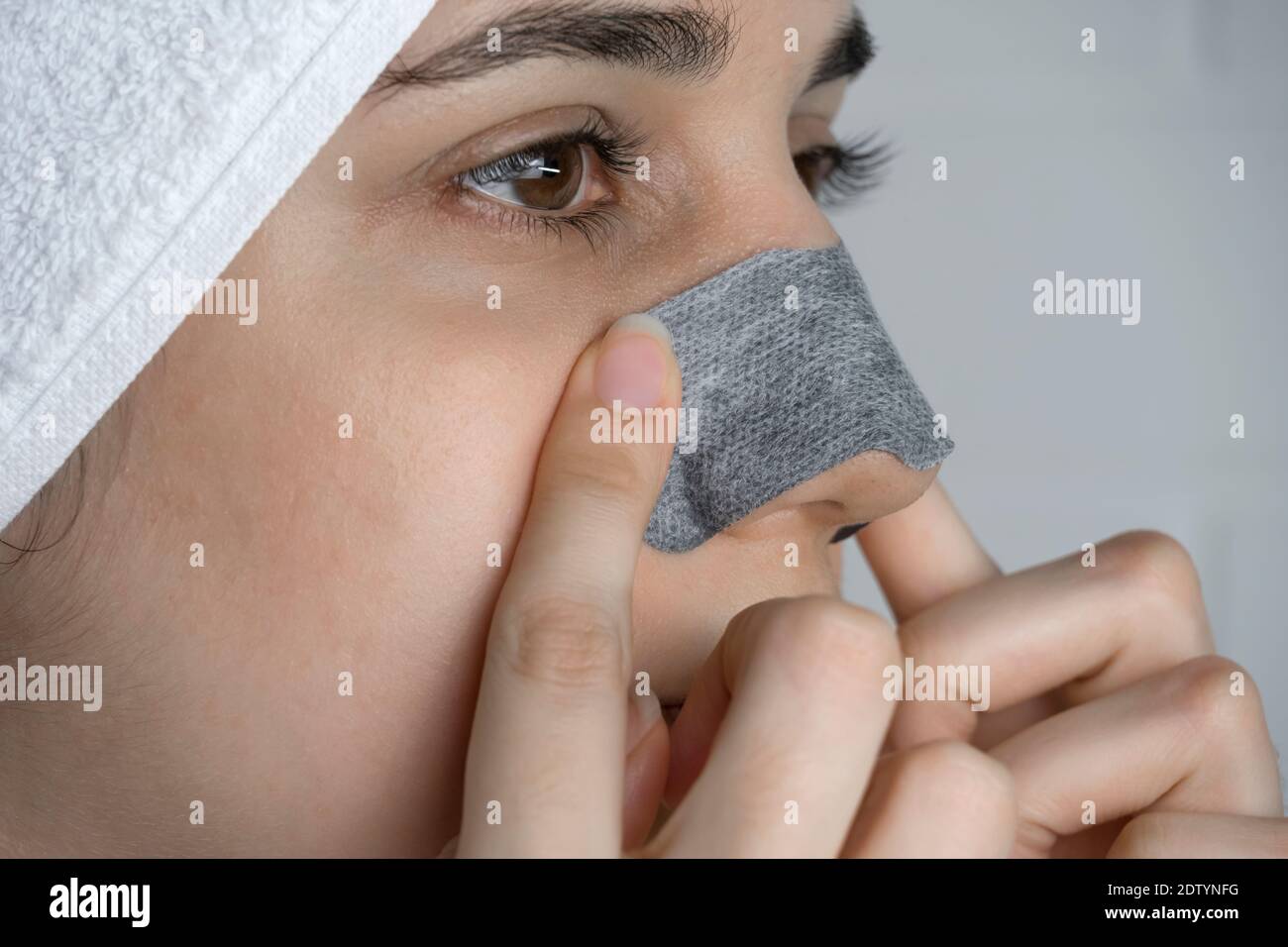 A woman sticks a cleansing strip on her nose. Black dots on the nose ...