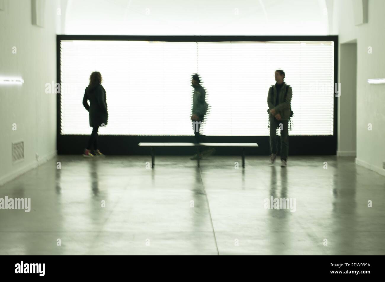 A view of three people standing far apart from each other inside of a ...