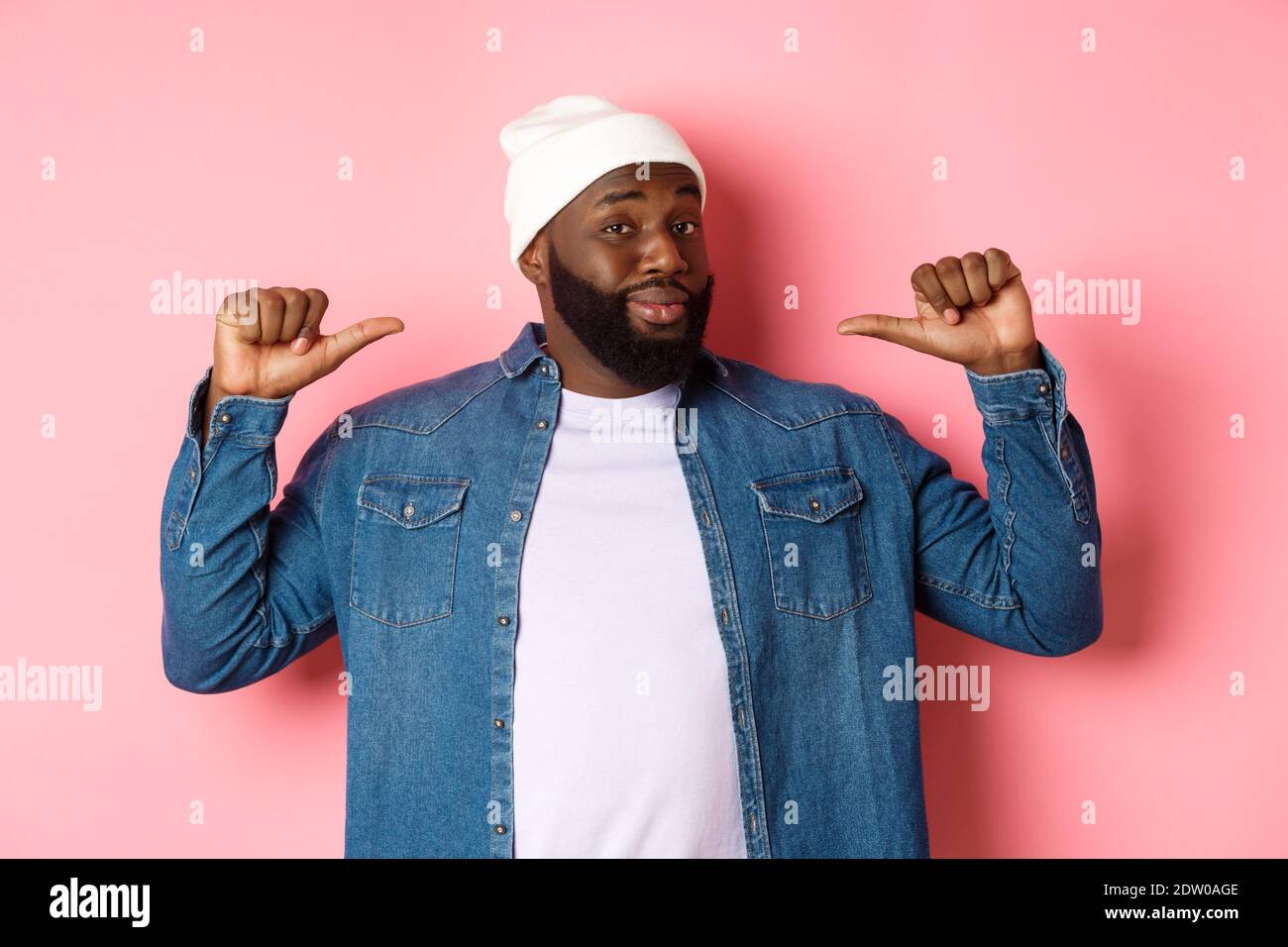 Confident and cheeky Black man pointing at himself, staring at camera ...