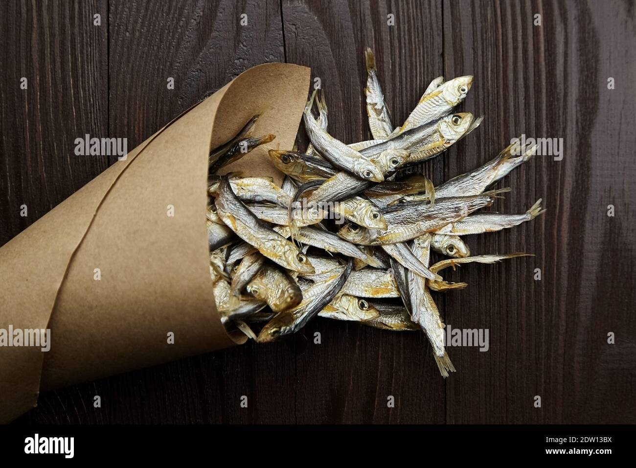Sun-dried salty small fish. Stockfish in paper bag on dark wooden ...
