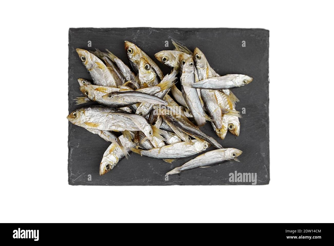 Small dried fish on black slate board isolated on white background ...