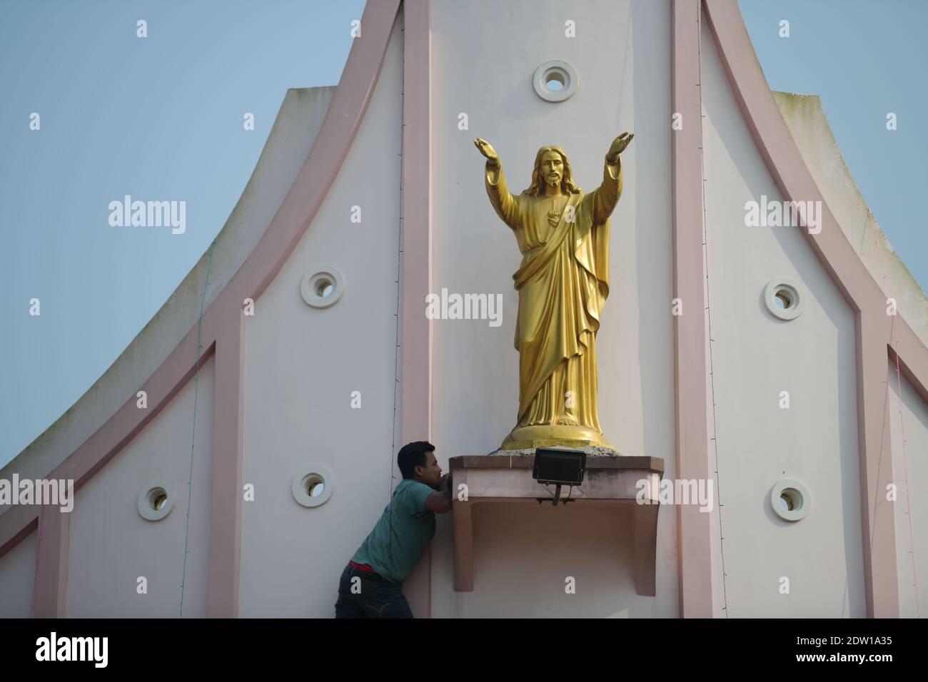 A worker cleaning a statue of Jesus Christ on top of a church in ...