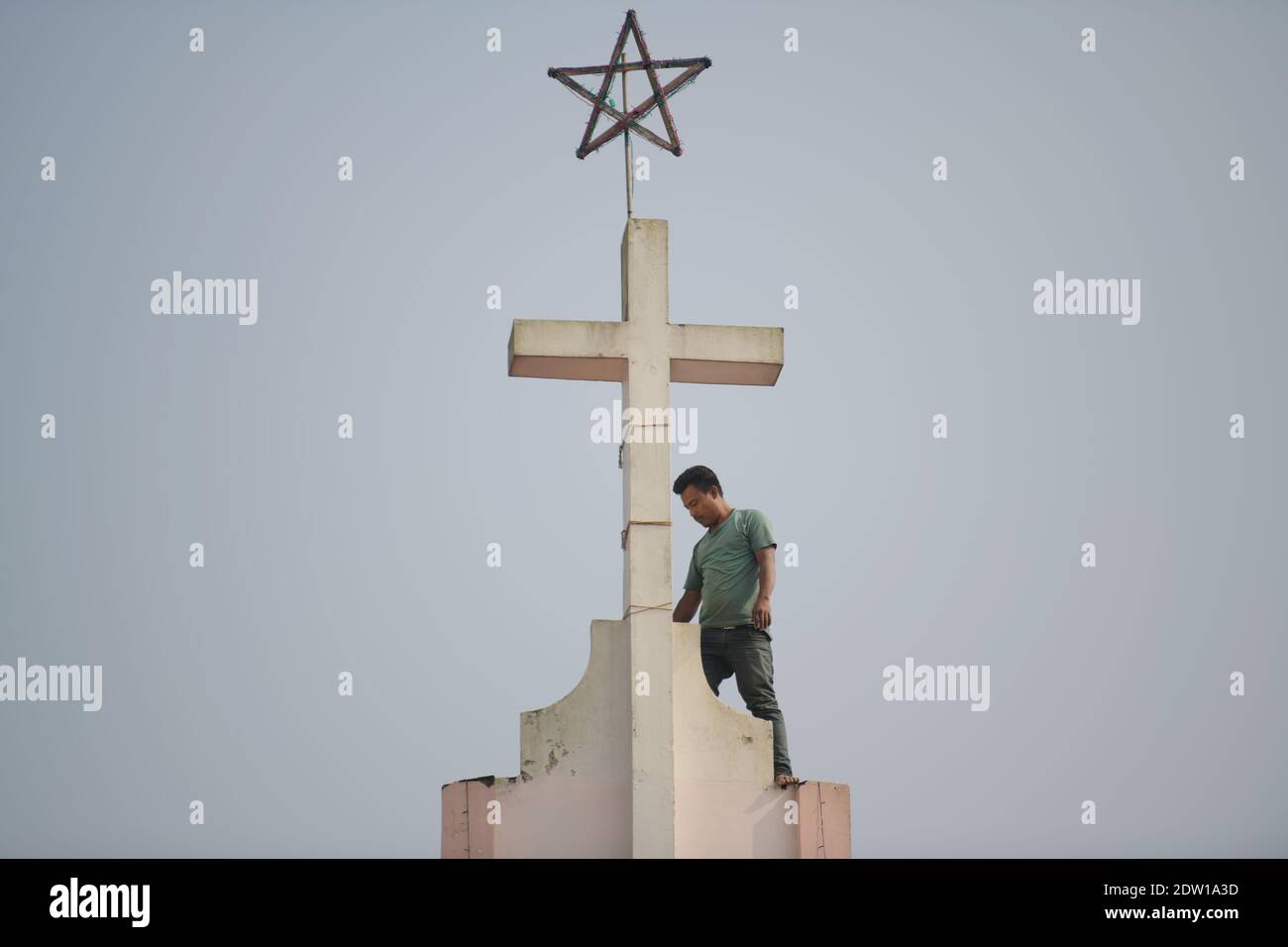 A worker cleaning a cross on top of a church in preparation for ...