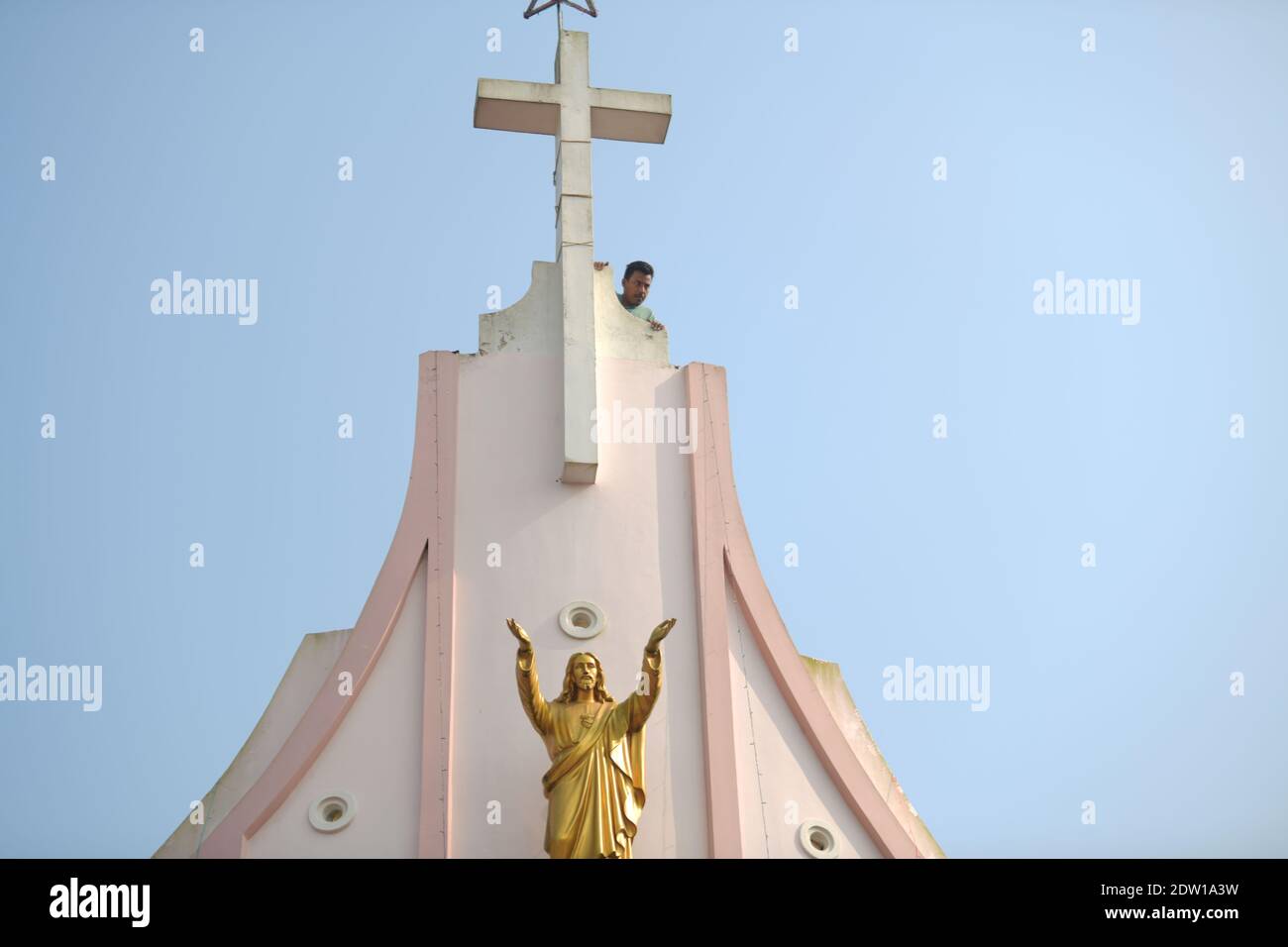 A worker cleaning a cross on top of a church in preparation for ...