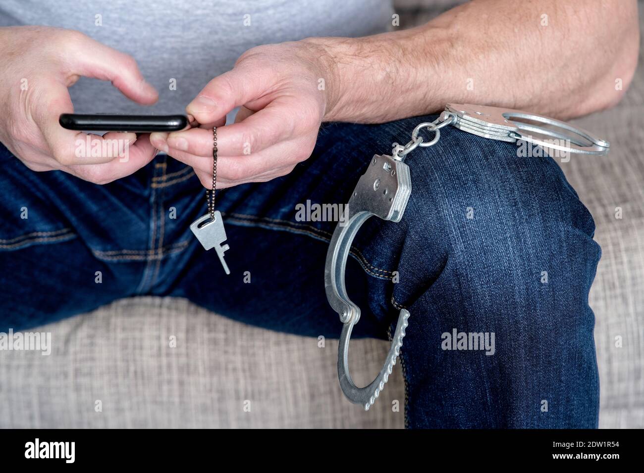 Close-up of handcuffs on the lap of a sitting police officer. In the ...