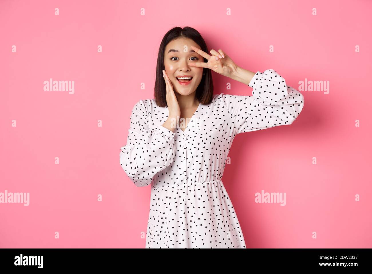 Beautiful and feminine asian woman showing kawaii sign on eye and ...