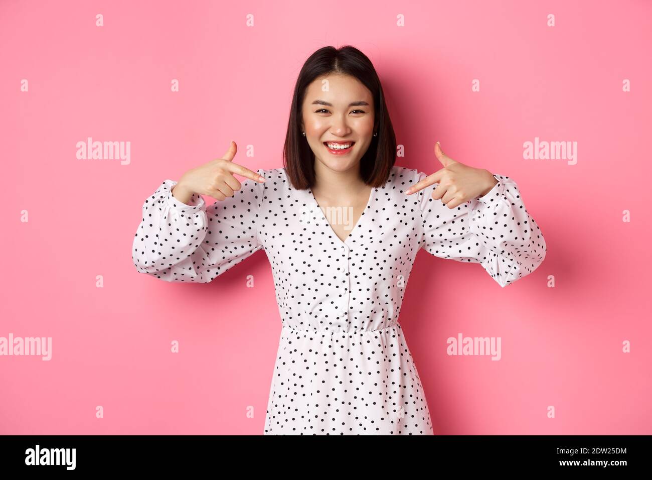 Beautiful korean woman pointing fingers at your logo and smiling ...