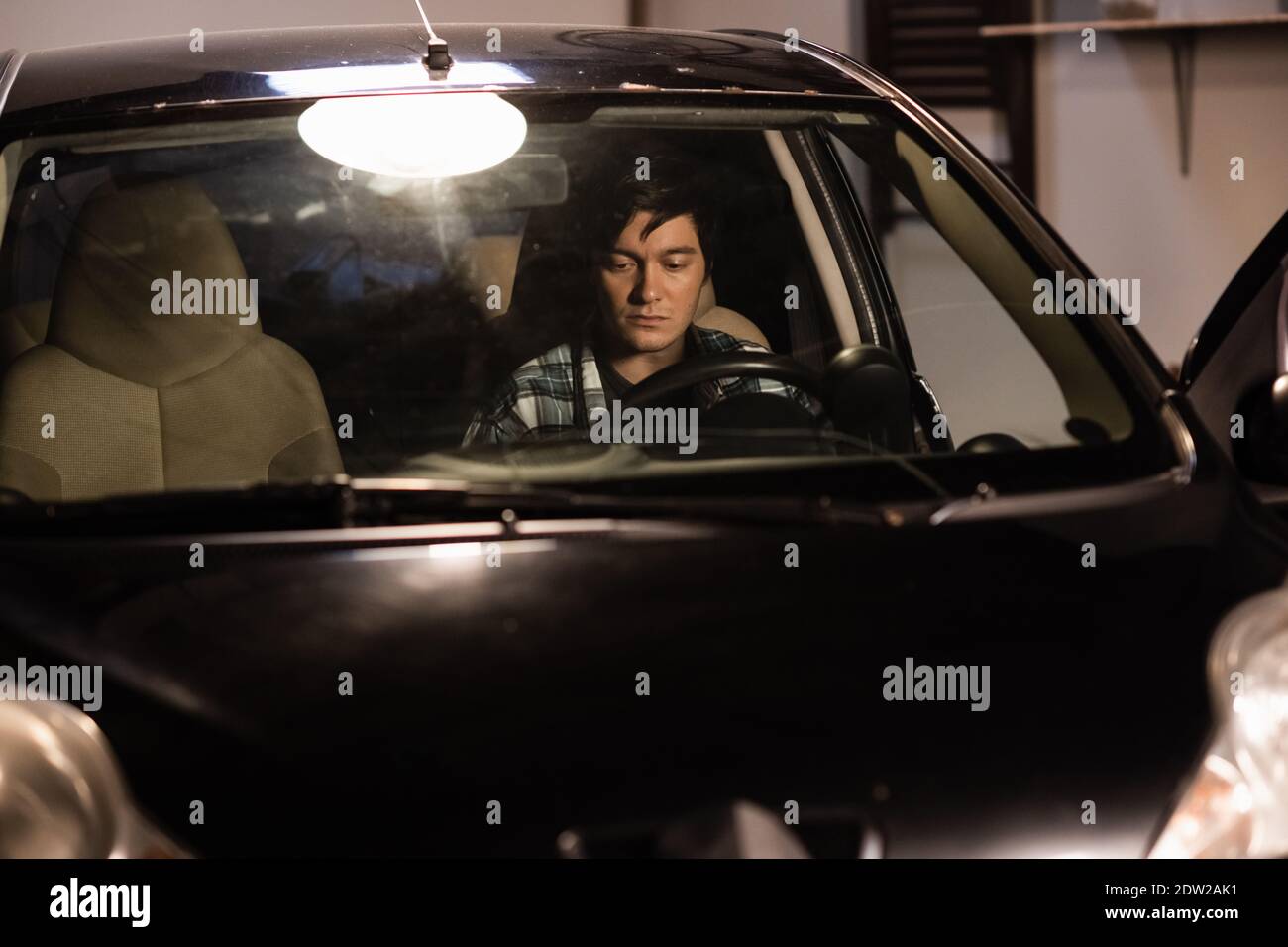 tired taxi driver parked the car in the garage, opened the door, sits ...