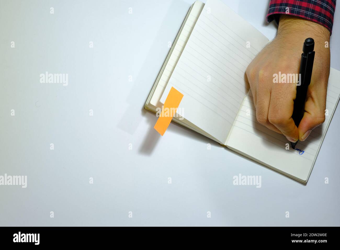 Man writing with black pencil. Orange book marker on the vintage ...
