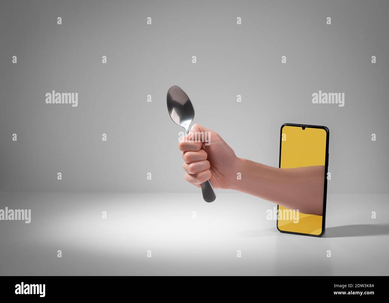 Hand giving a silver spoon from out of a phone screen Stock Photo - Alamy