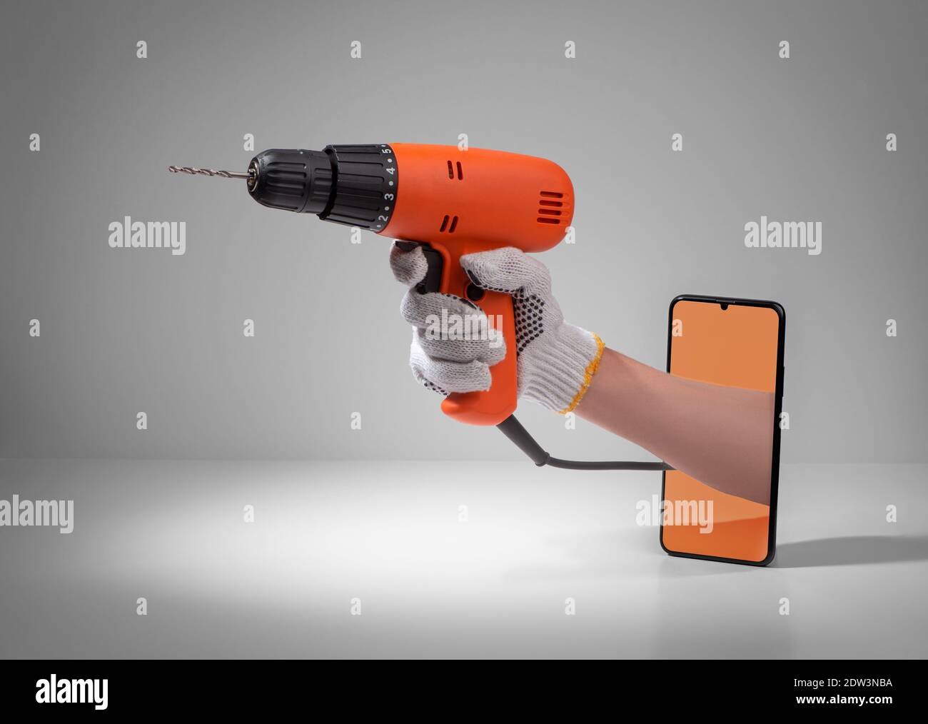 Hand holding a corded drill from out of a phone screen Stock Photo - Alamy
