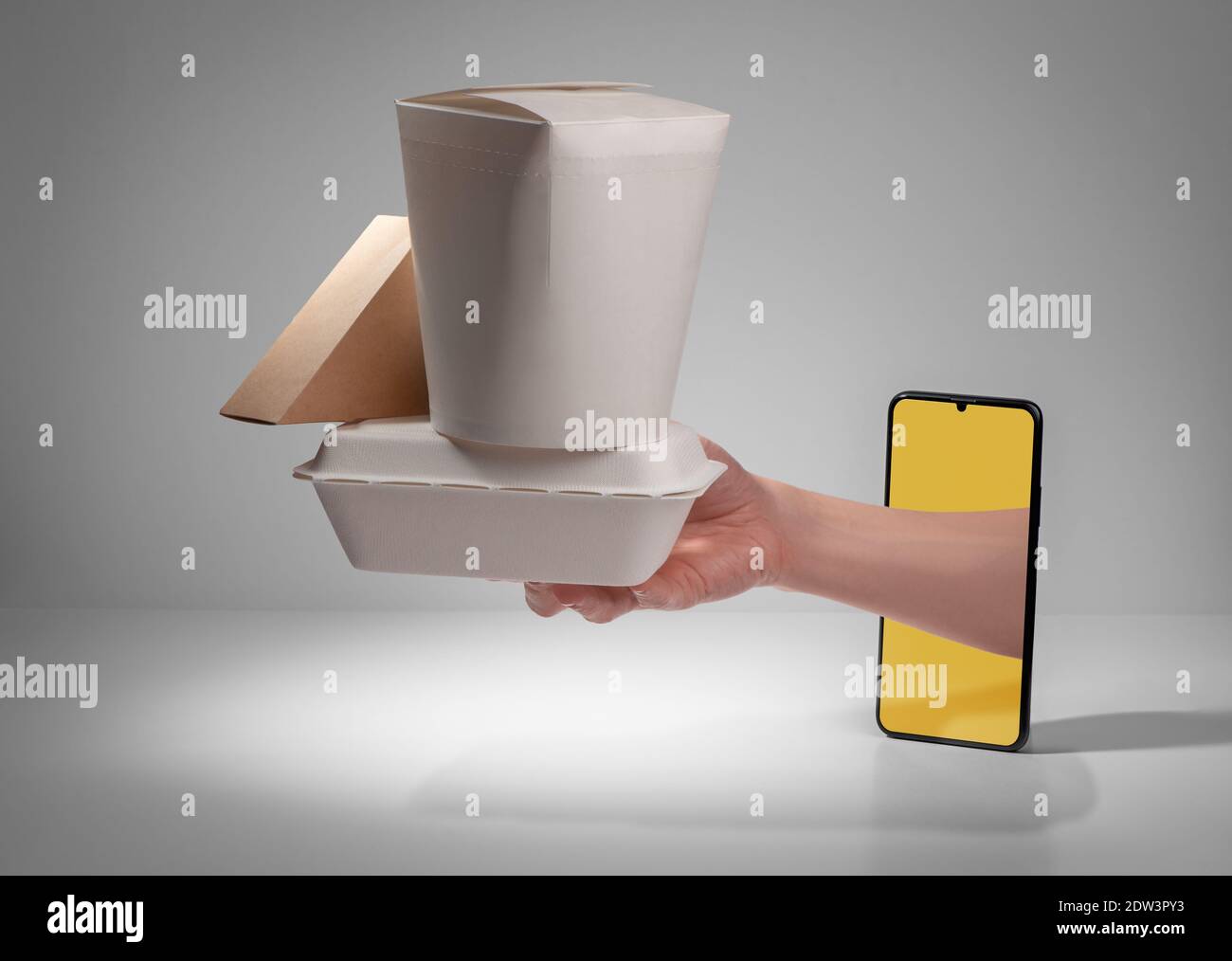 Hand giving pile of packed food through a phone screen Stock Photo - Alamy