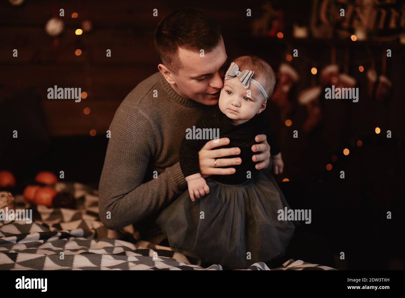 Merry Christmas and Happy Holidays. Cheerful father hugging cute baby daughter girl on bed near ...