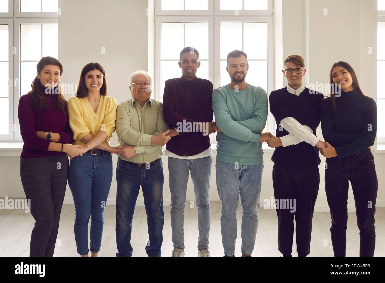 Group of happy diverse people standing together, holding hands and ...