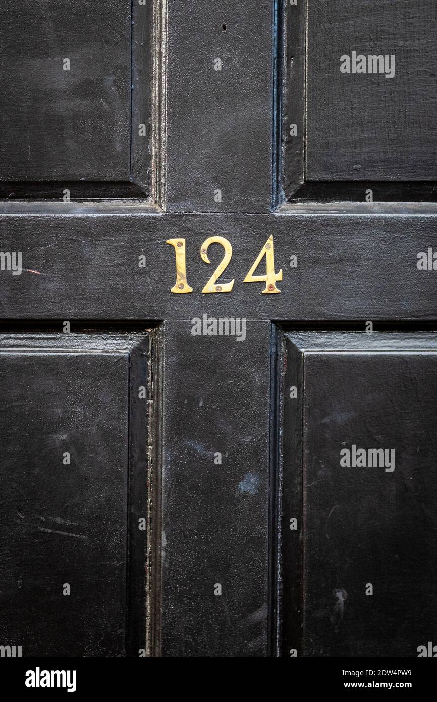 Golden metal digits on a black wooden front door form number 124 Stock ...