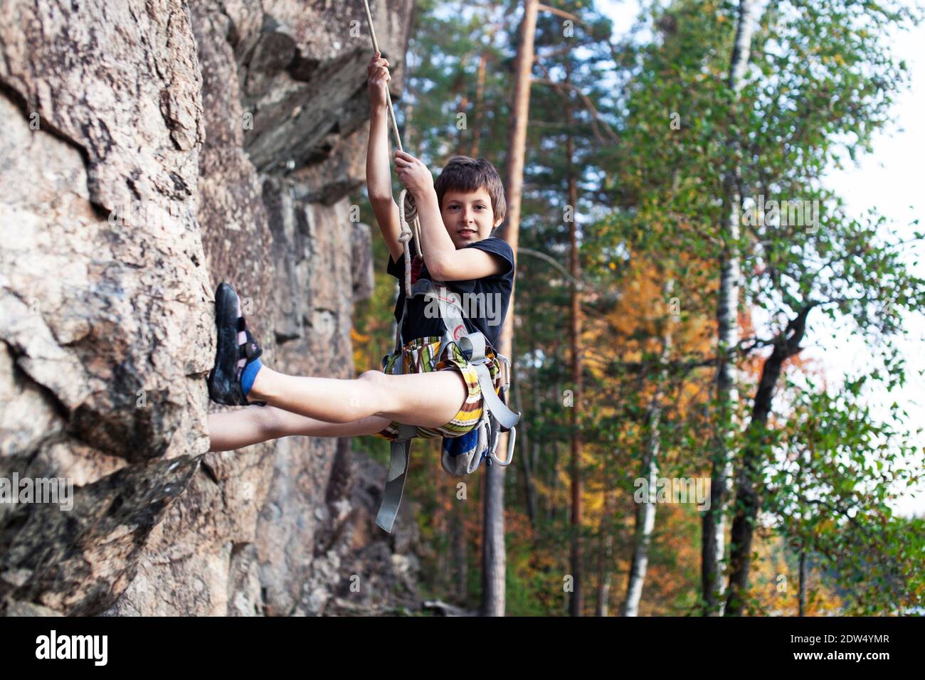 cute teen kid climbing on rock with insurance, lifestyle sport people ...