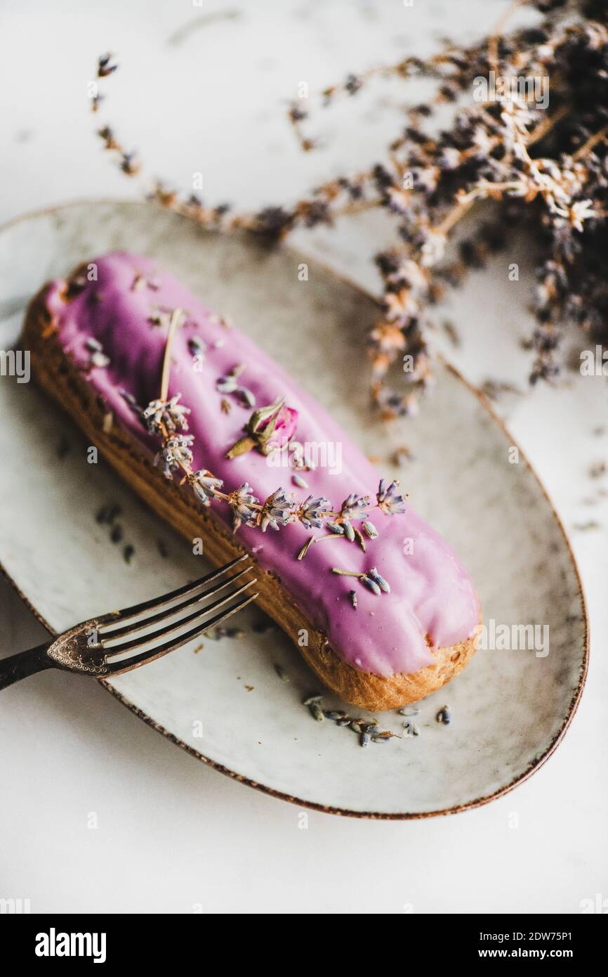 Lavender eclair decorated with purple flowers and branches on oval ...