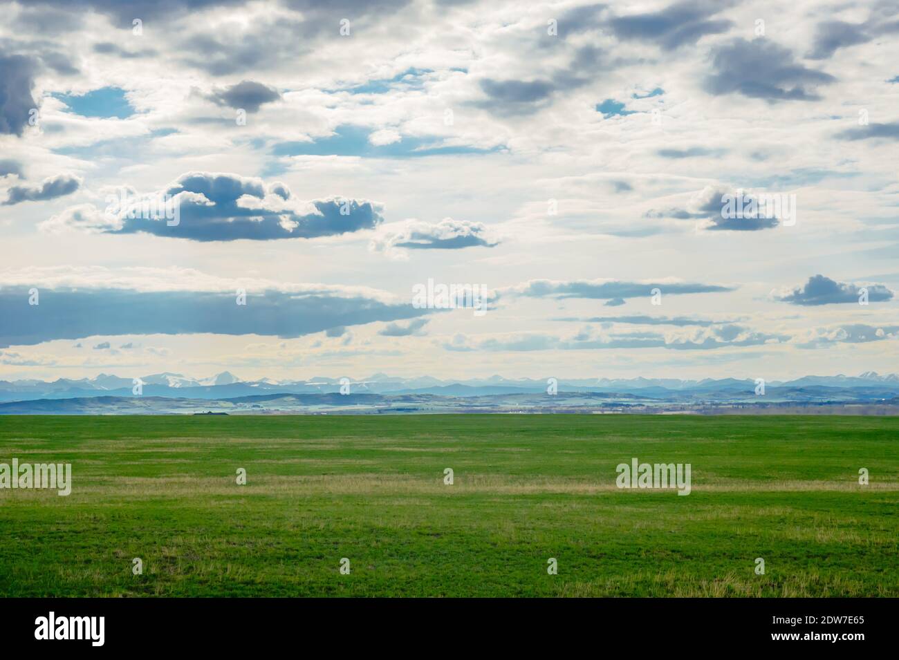 Prairie landscape with mountains in distance under low clouds, in ...