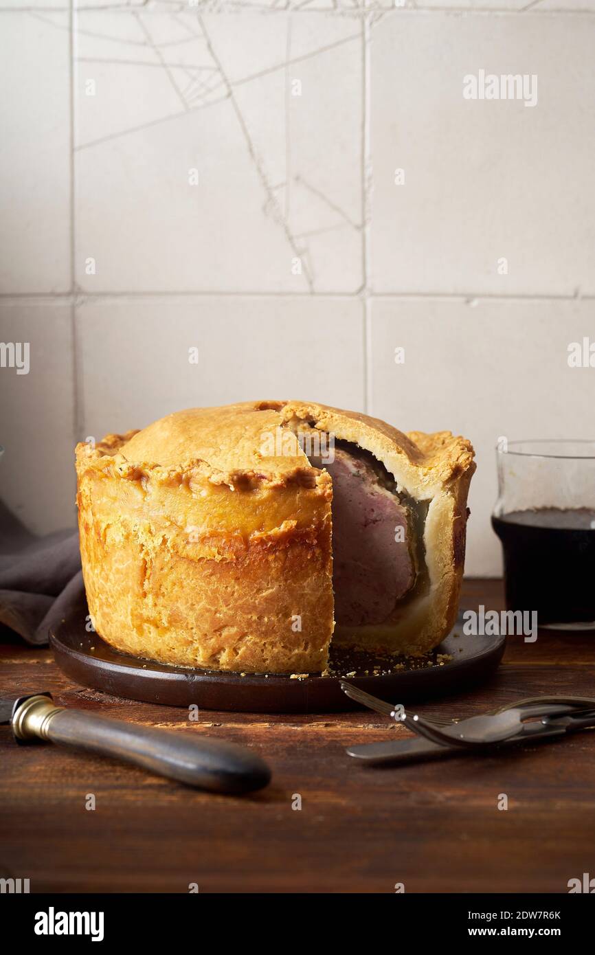 Traditional british raised pork pie with bacon and herbs on the kitchen ...