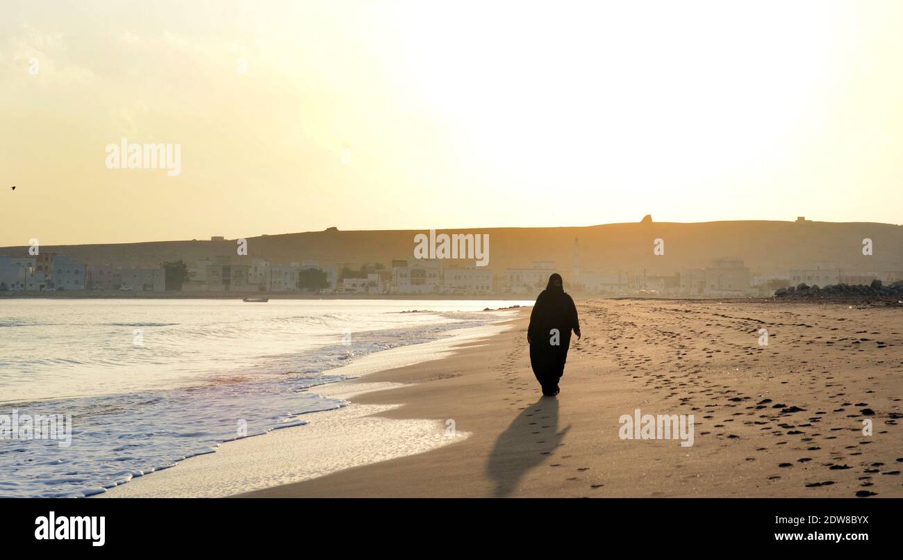An Omani woman walking on the Barka beach in Oman Stock Photo - Alamy