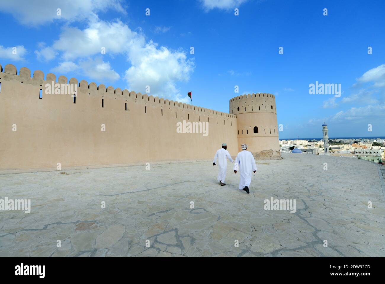 Omani men walking by the Sunaysilah Fort in Sur, Oman Stock Photo - Alamy