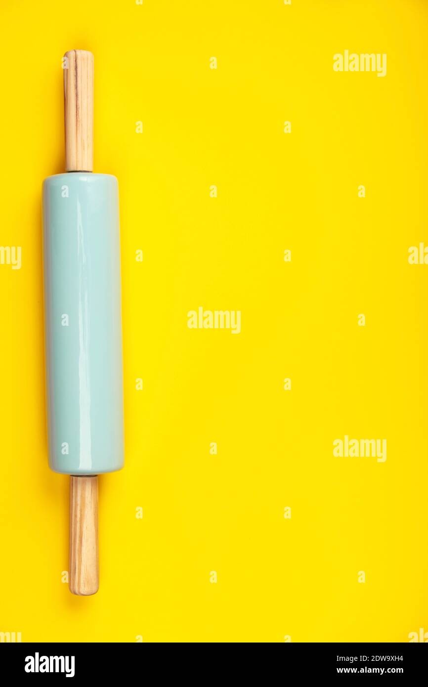 Blue rolling pin on yellow background, flat lay. Baking or cooking ...