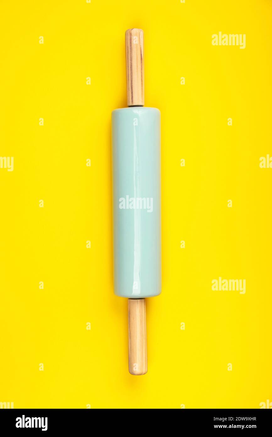 Blue rolling pin on yellow background, flat lay. Baking or cooking ...