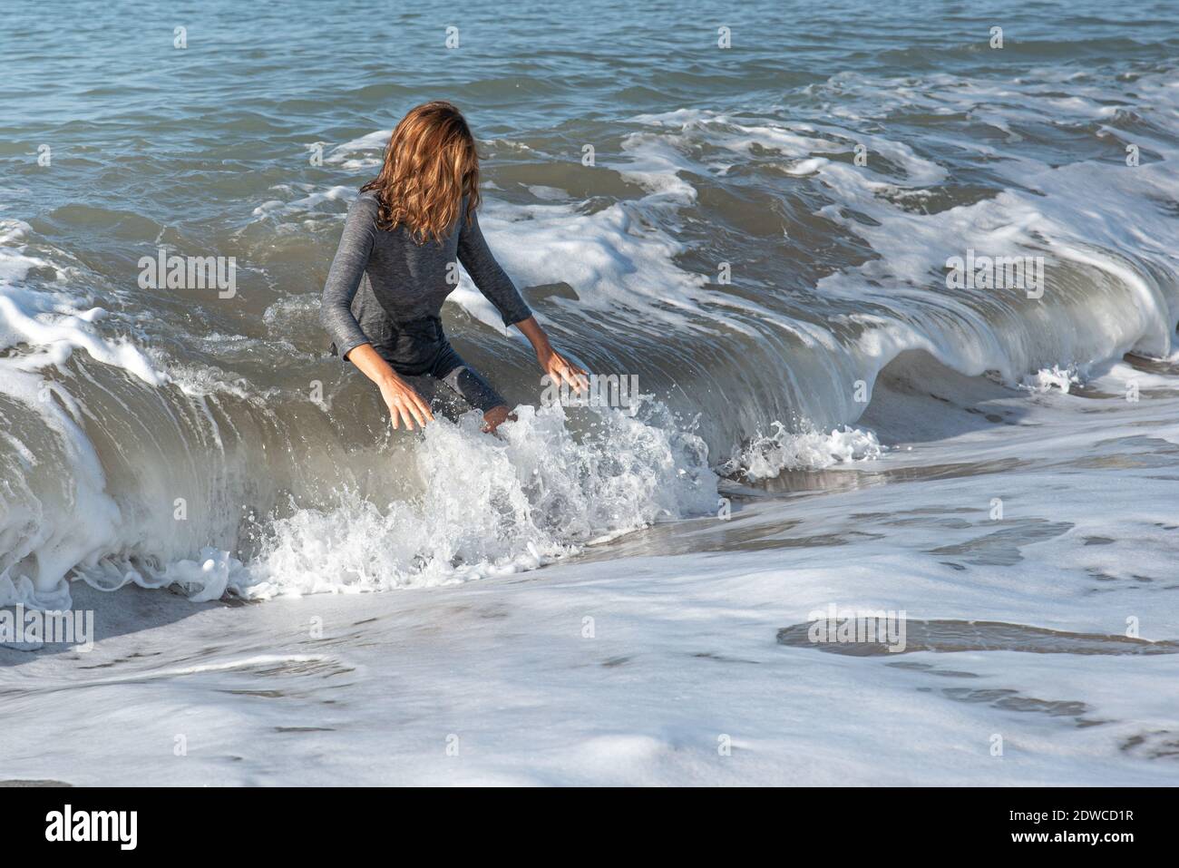 Woman coming out of the sea in a wet dress after a swim at the beach ...
