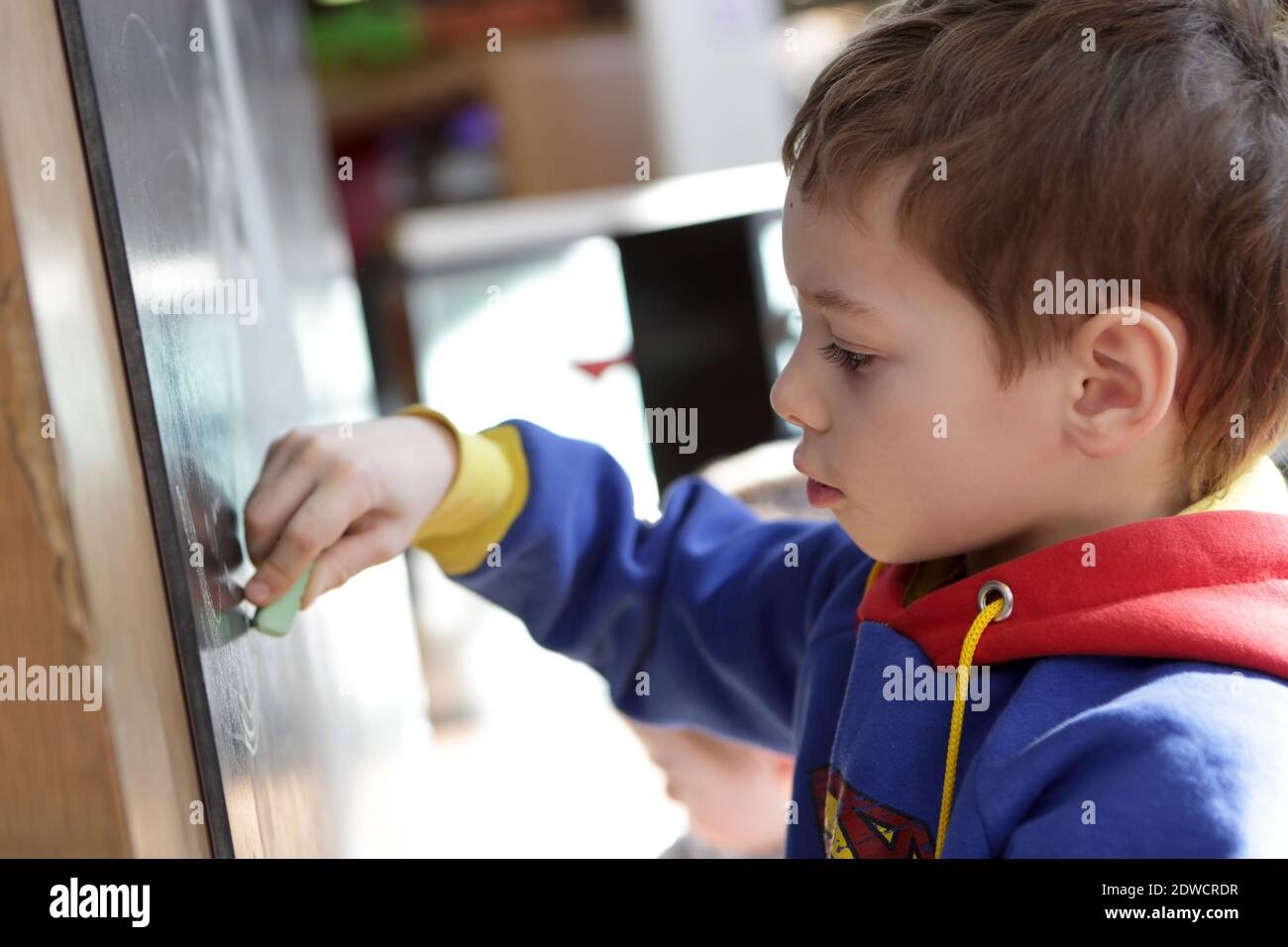 Kid draws a chalk on a blackboard Stock Photo - Alamy