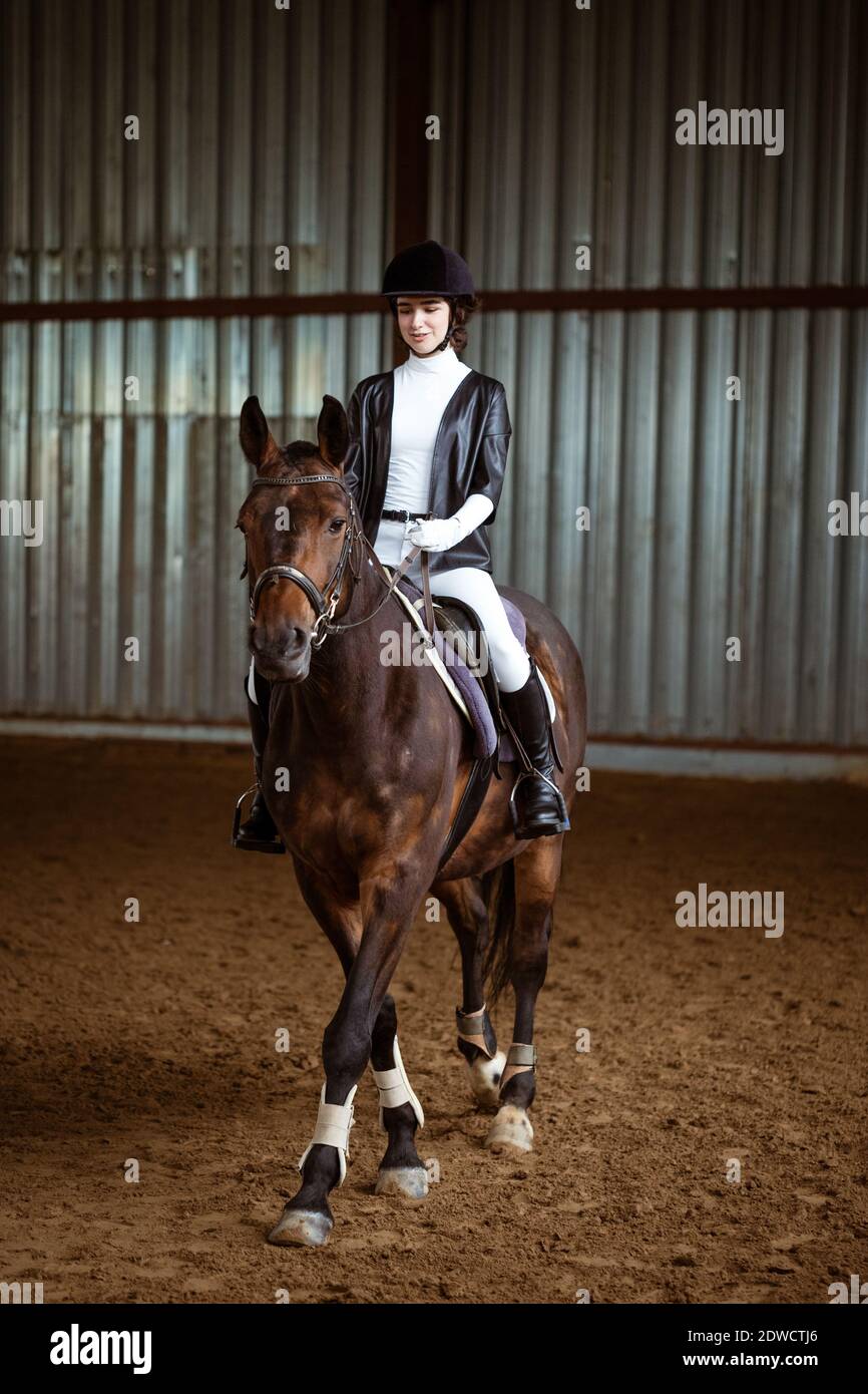 Young woman in special uniform and helmet riding horse. Equestrian ...