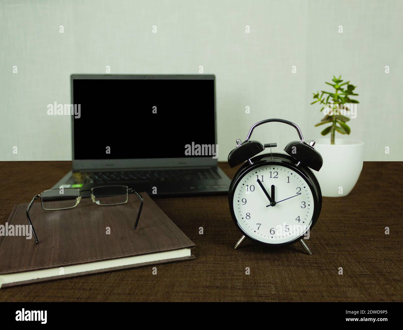 The hands of the clock indicate lunchtime. Clock on laptop background ...