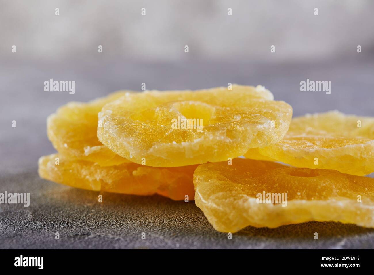 Yellow candied pineapple rings on a gray concrete background. Color ...