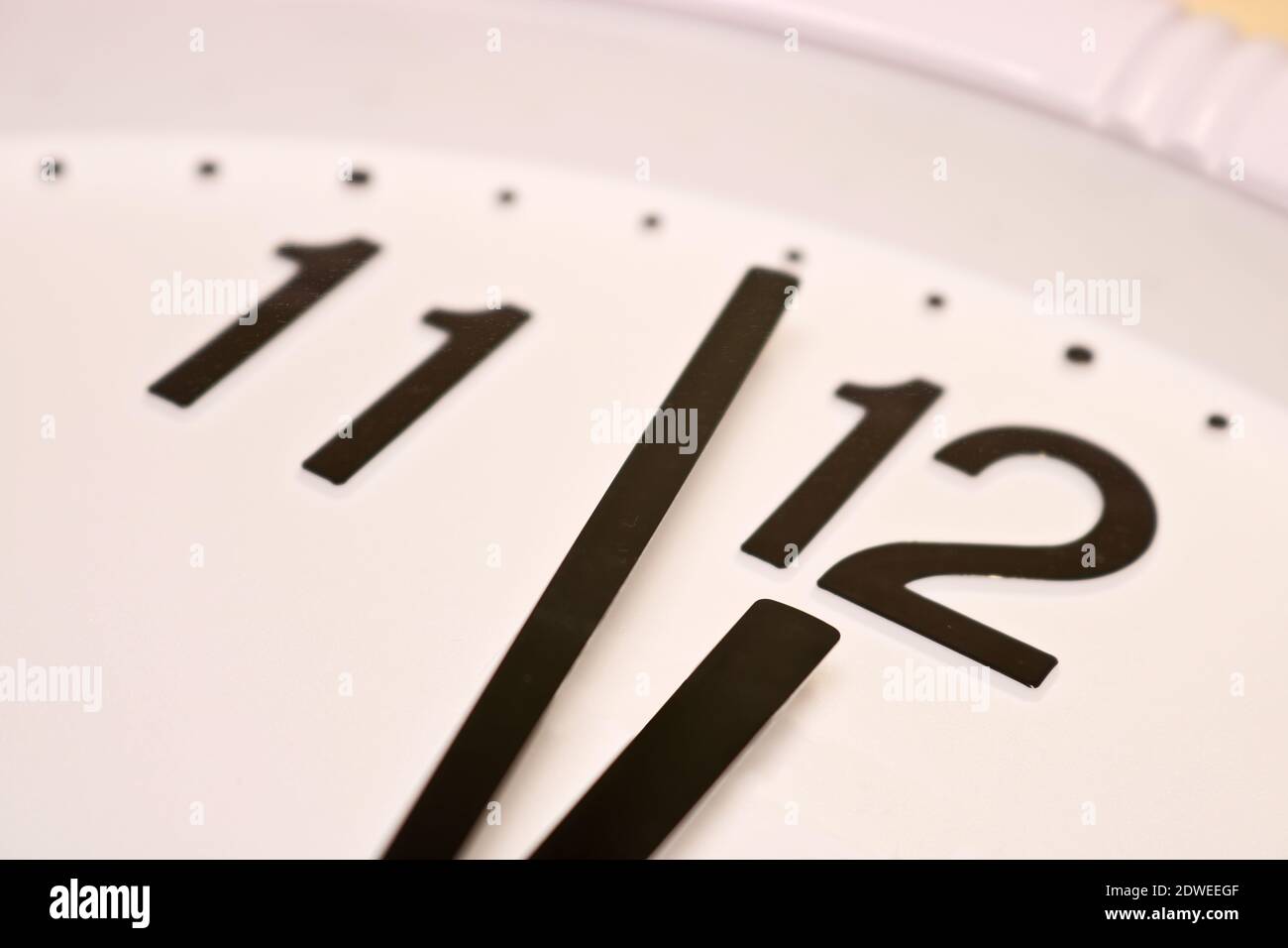 Dial of an analog clock close up. The time is 23:59. White dial, black ...