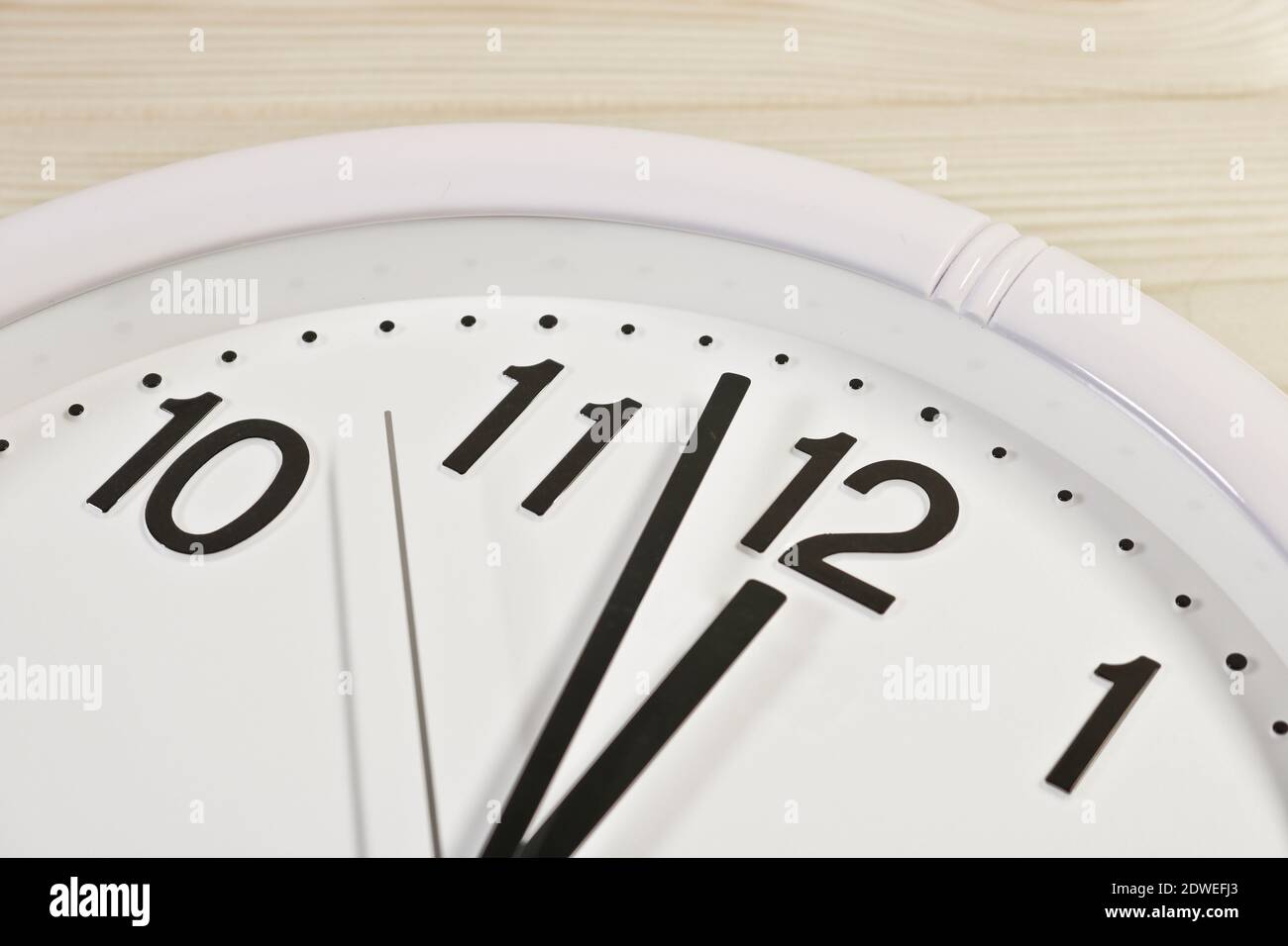 Dial of an analog clock close up on a wooden background. The time is 23 ...