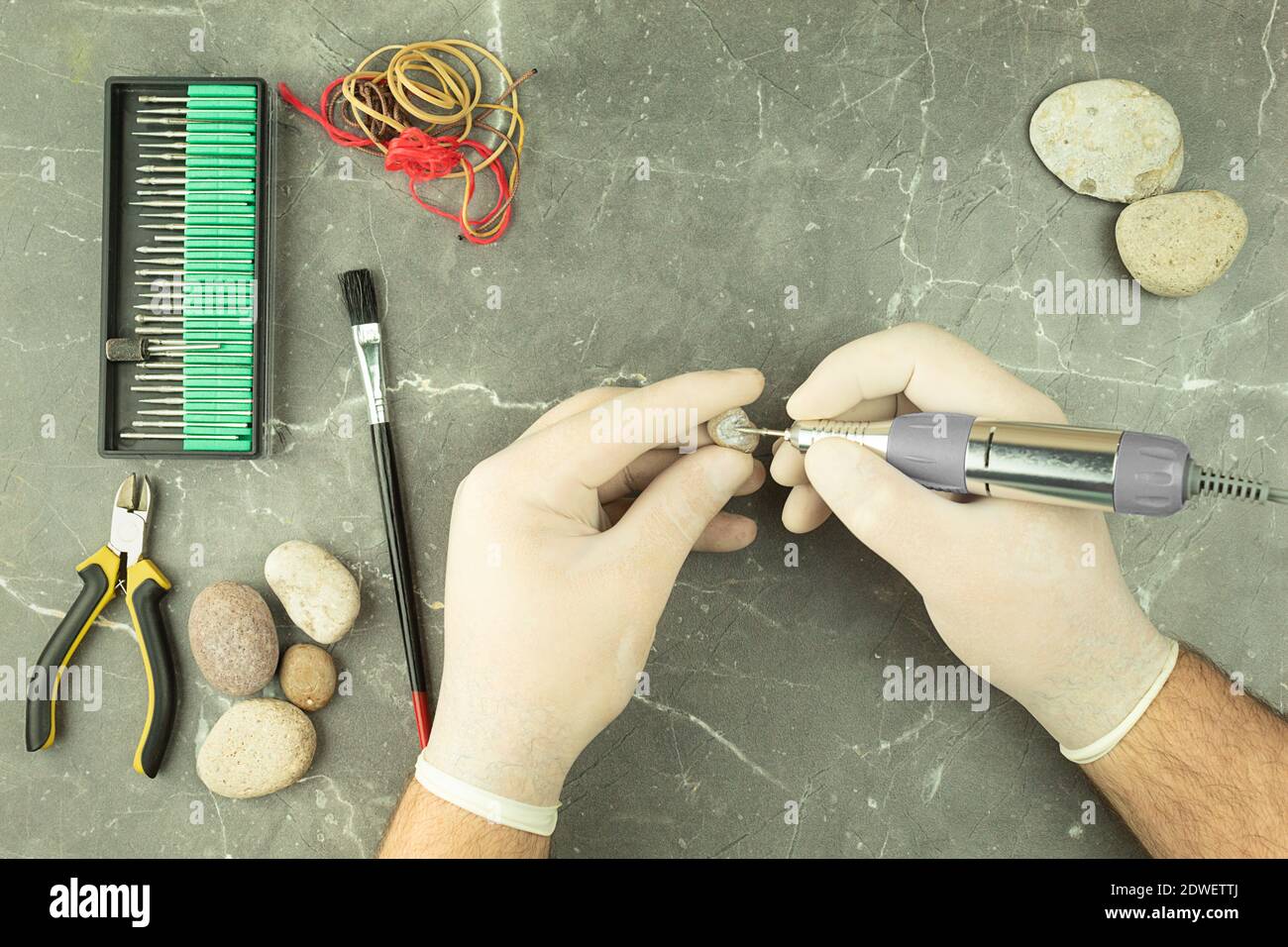 The hands of a man engrave the stone with the help of an engraver ...