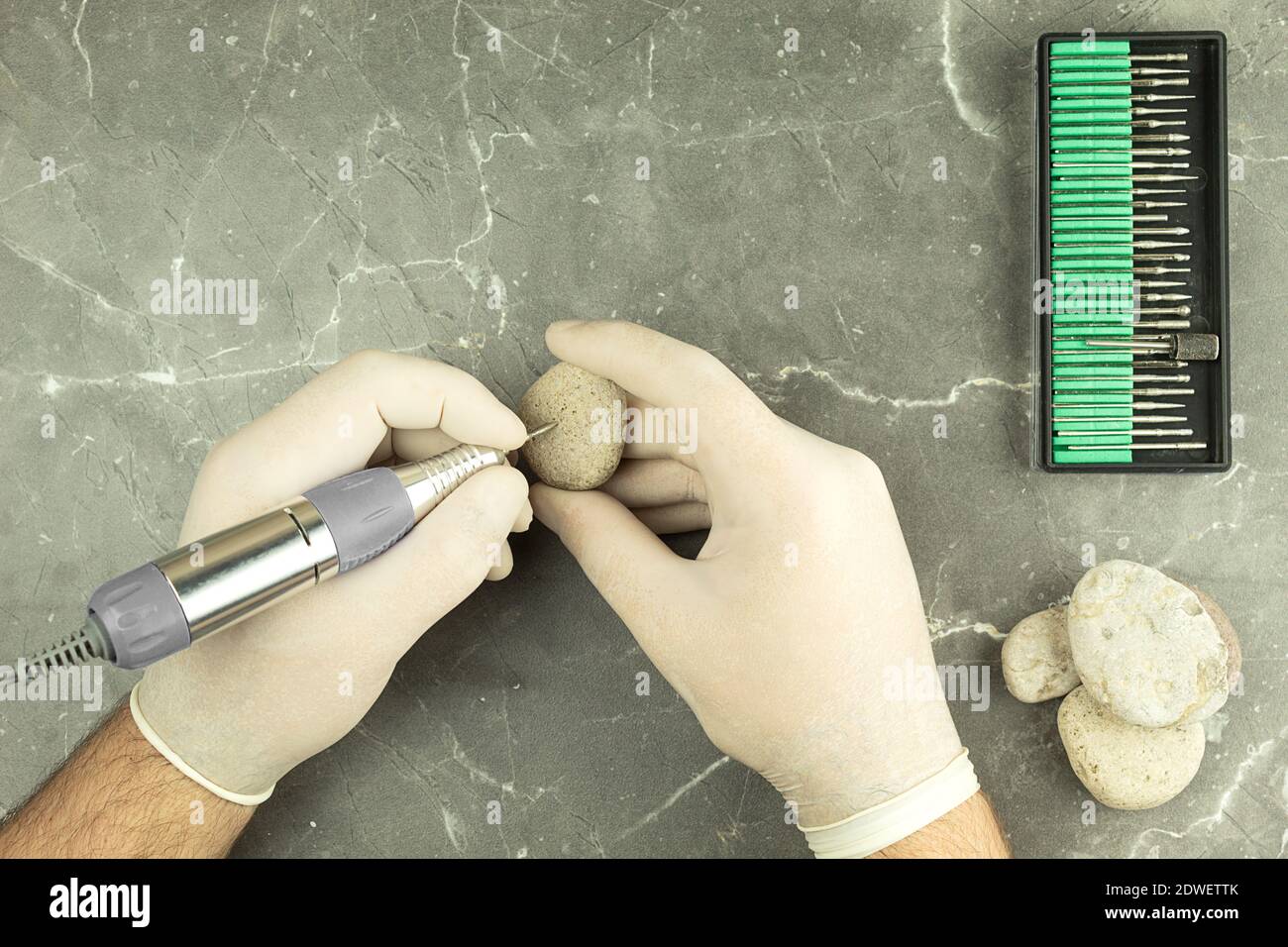 The hands of a man engrave the stone with the help of an engraver ...