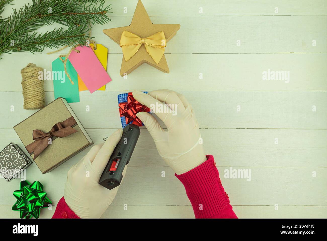 Women's hands in protective gloves are packing gifts for the holidays ...