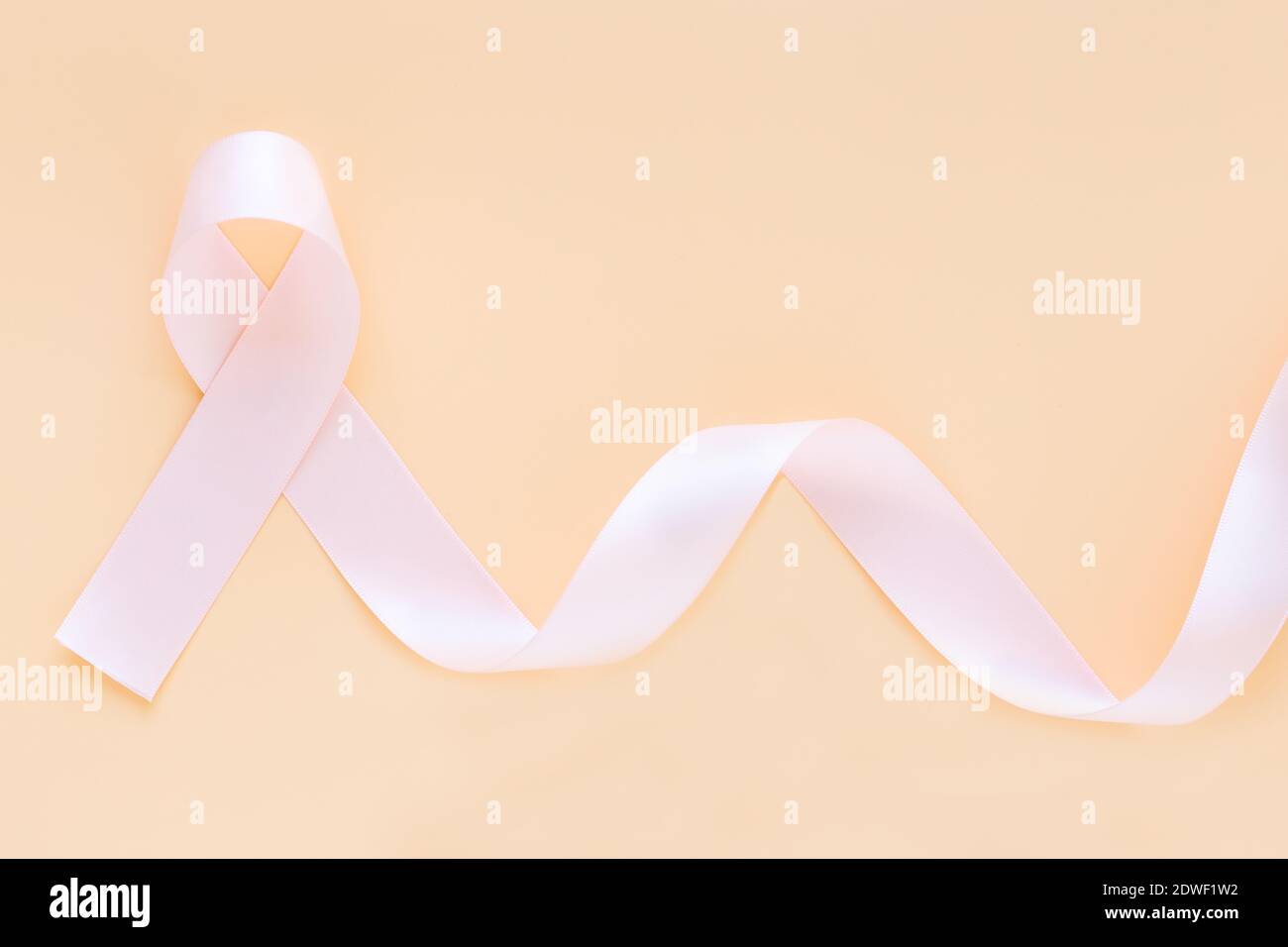 Peach color ribbon curl on pastel orange or beige color background with ...