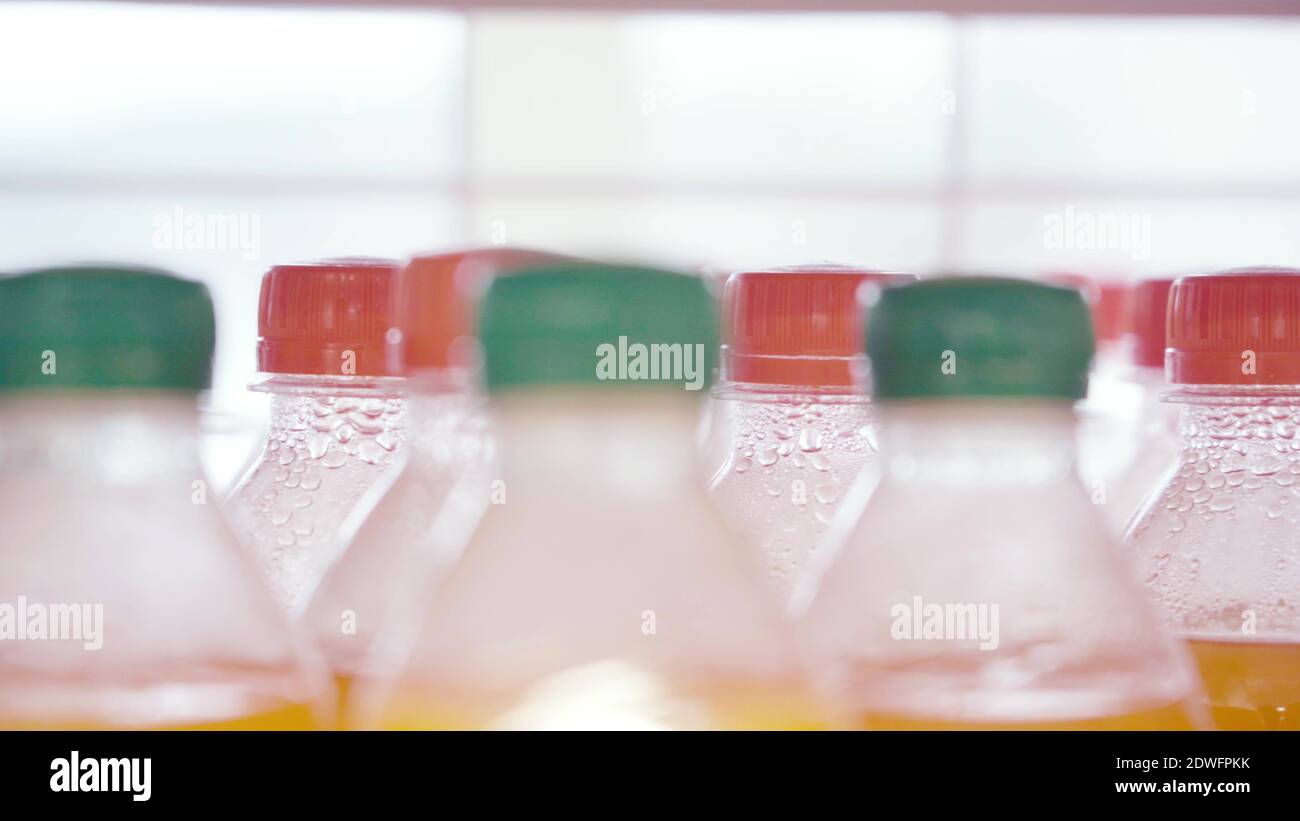 Lots of plastic drinks bottles in the shop by the window. CLOSE-UP. Row of carbonated soft drink ...