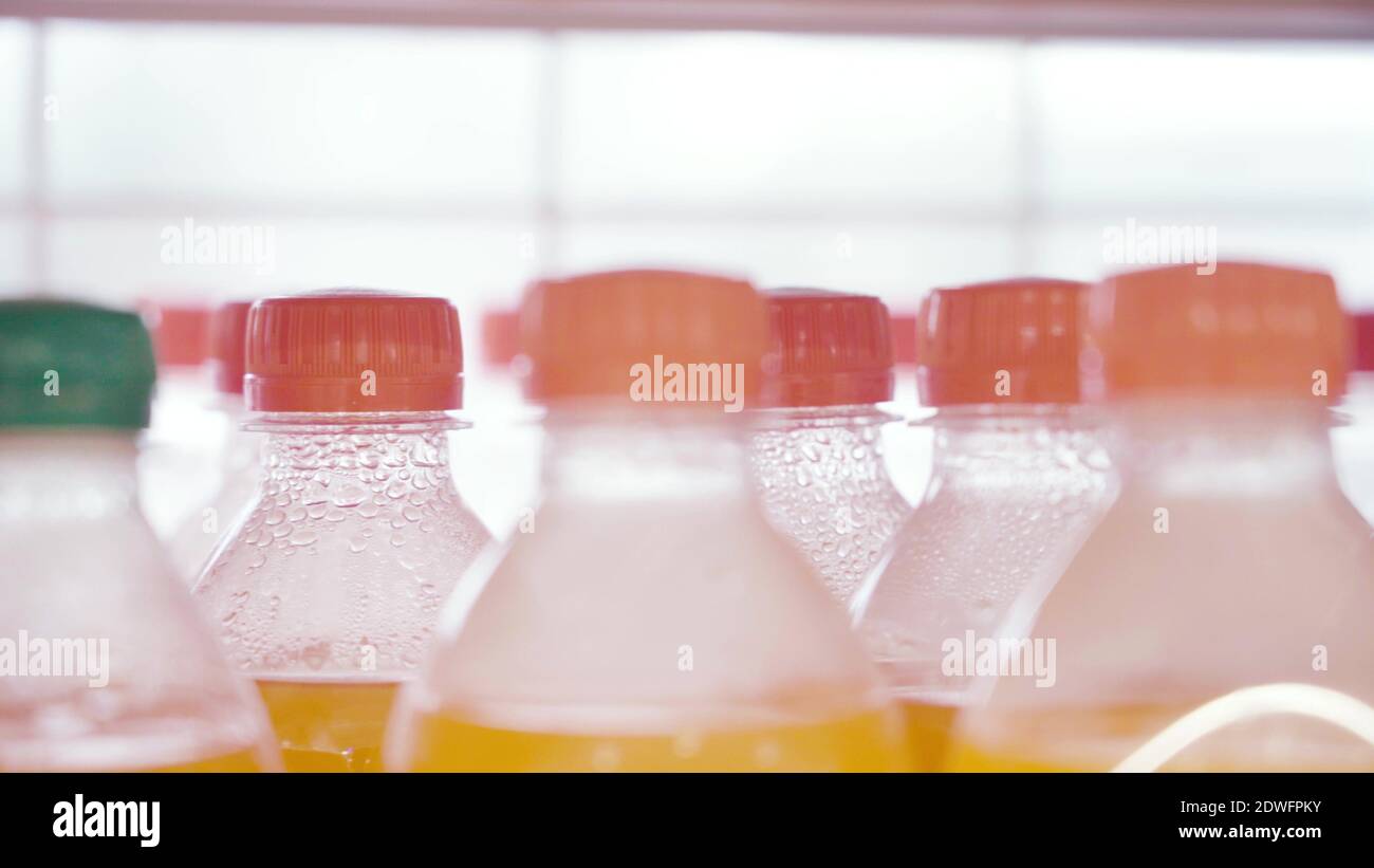 Lots of plastic drinks bottles in the shop by the window. CLOSE-UP. Row of carbonated soft drink ...
