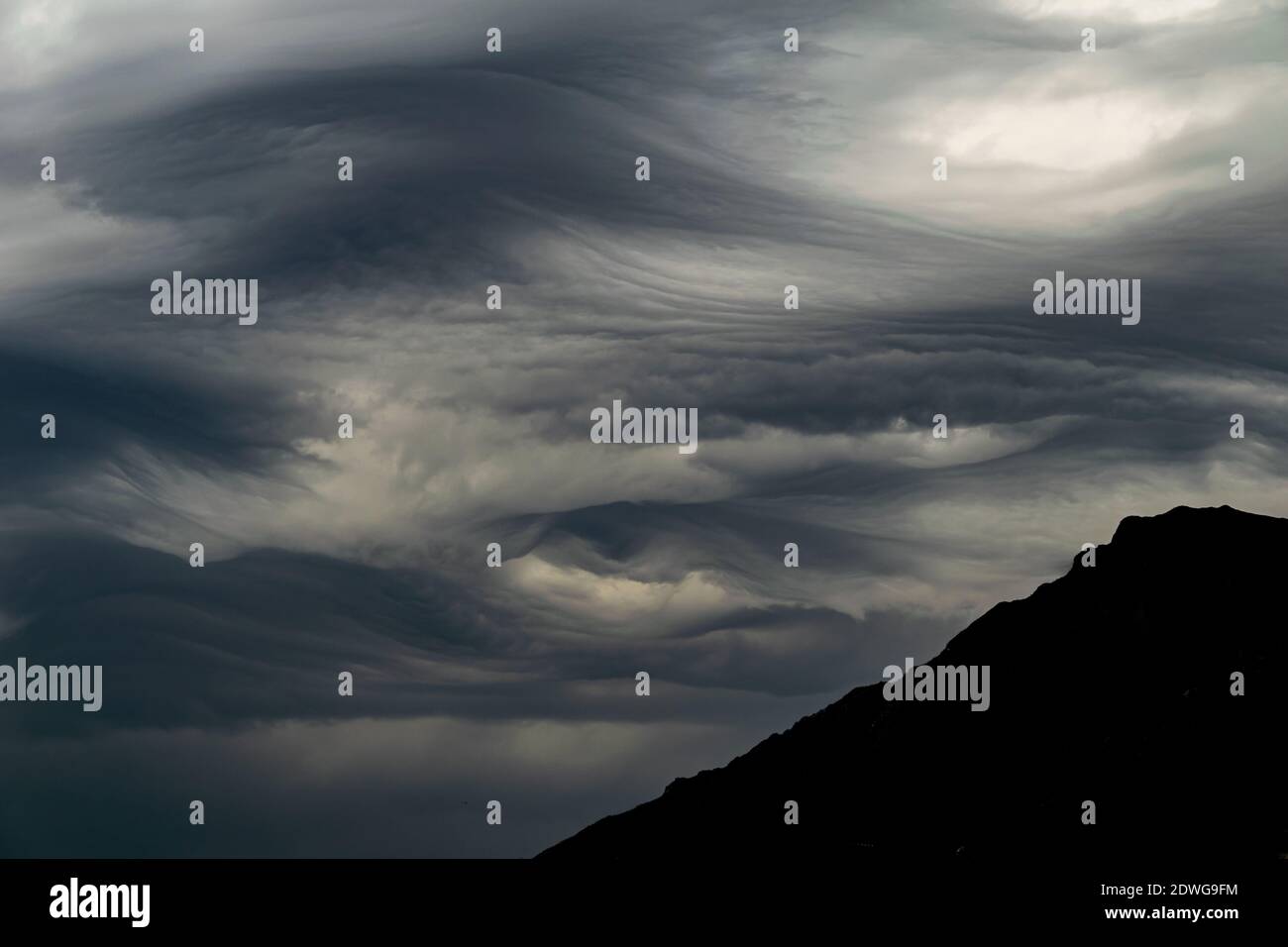 stormy weather front with thick grey clouds with a mountain silhouette ...