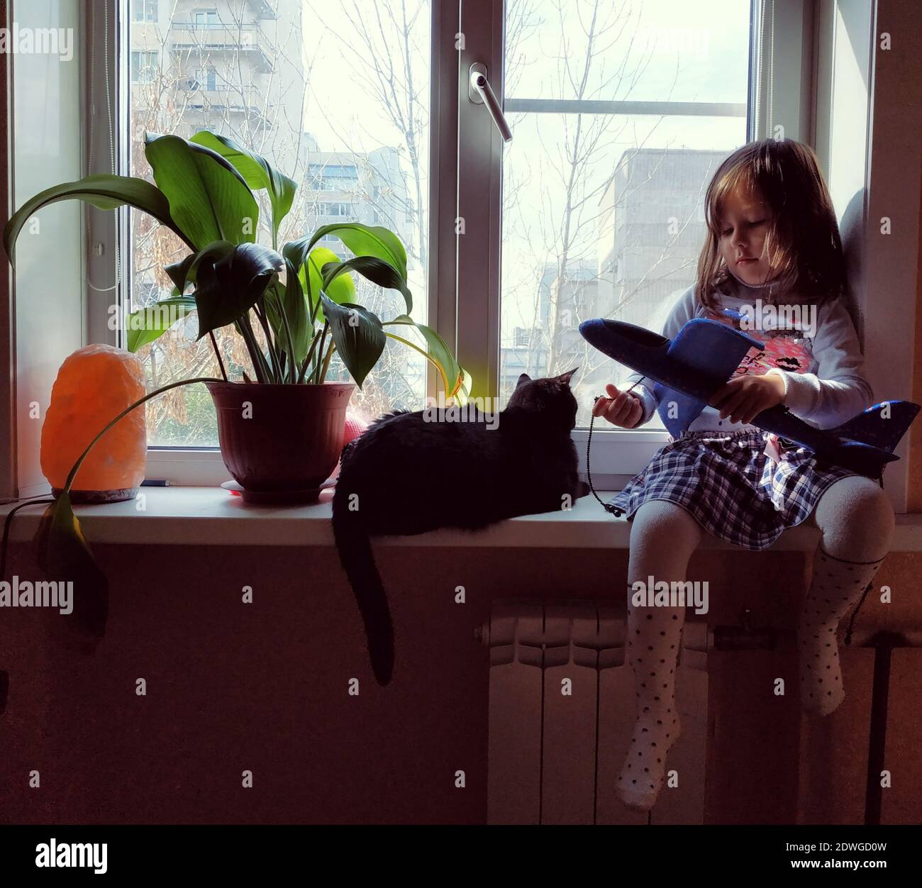 Full Length Of Girl With Model Airplane Sitting On Window Sill At Home ...