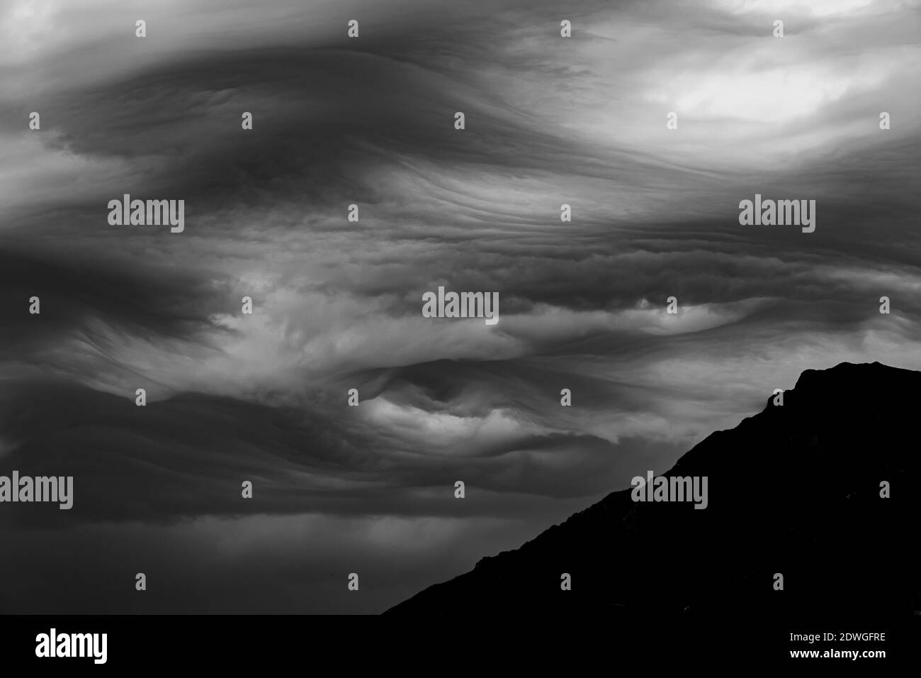 stormy weather front with thick grey clouds with a mountain silhouette ...