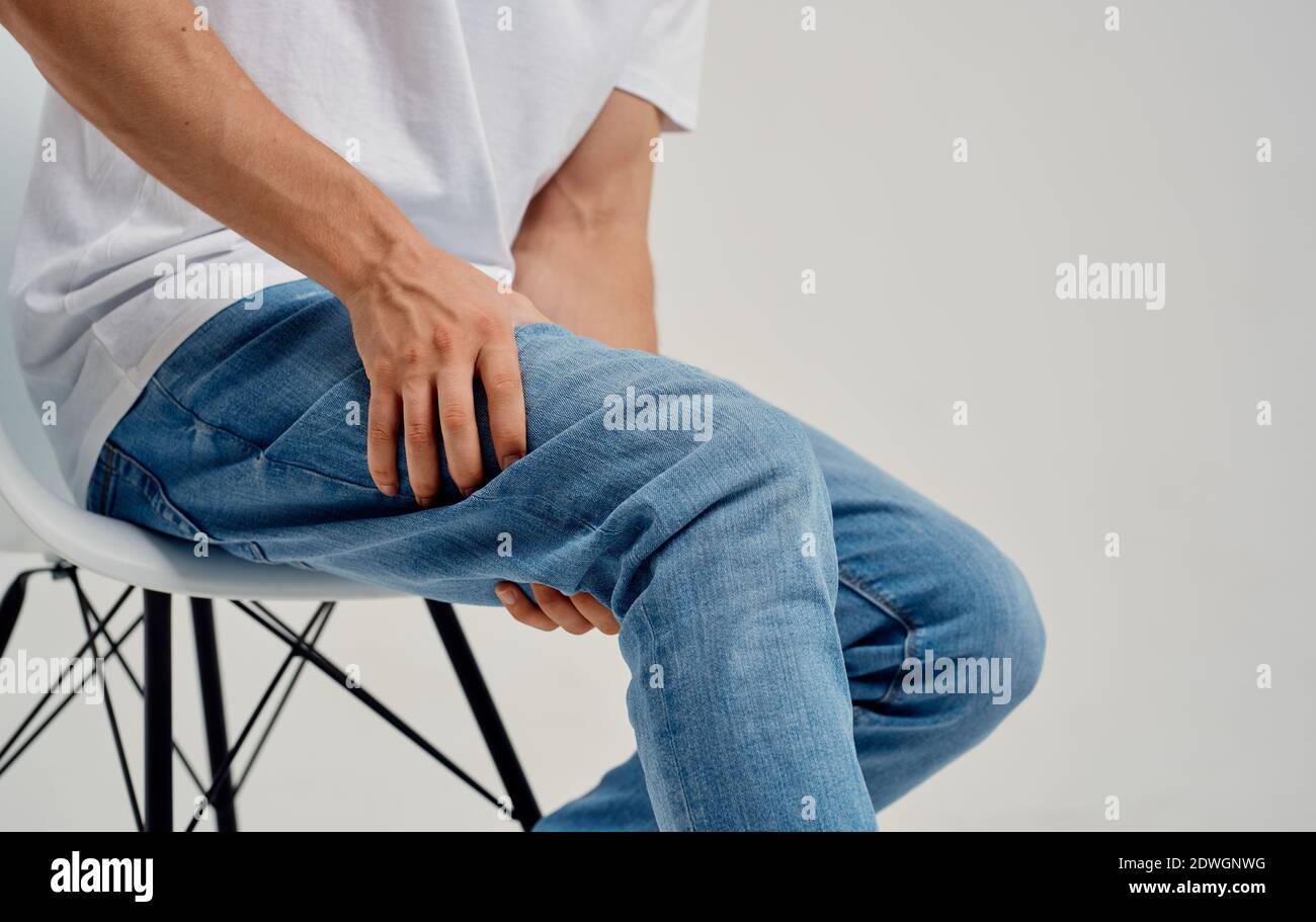the guy touches his leg with his hands on a light background knee pain ...