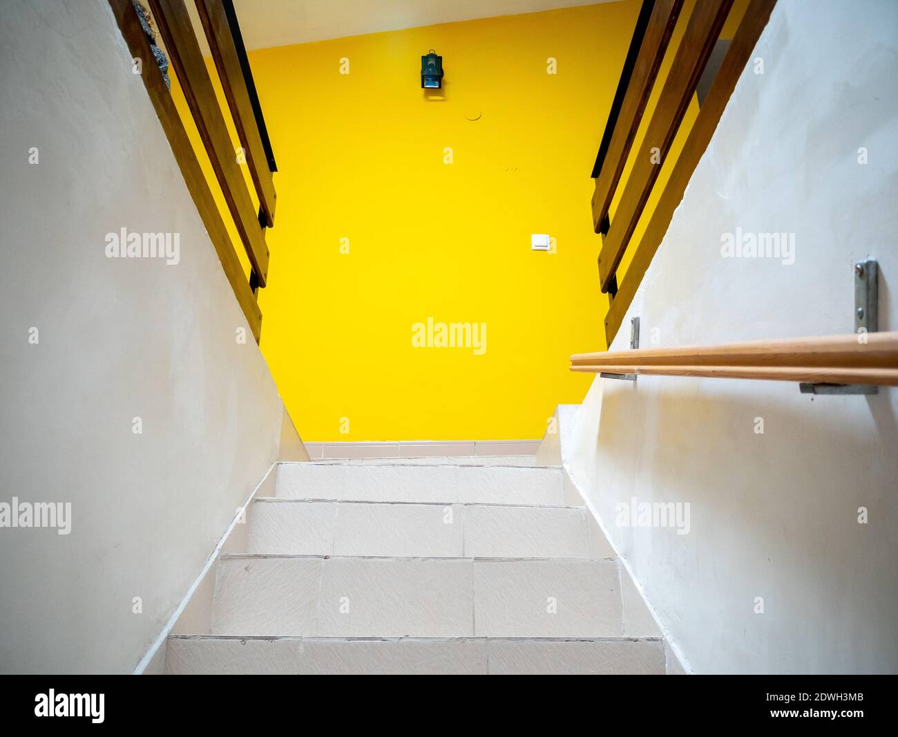 A house hall with yellow walls, white stairs with wooden handrails ...
