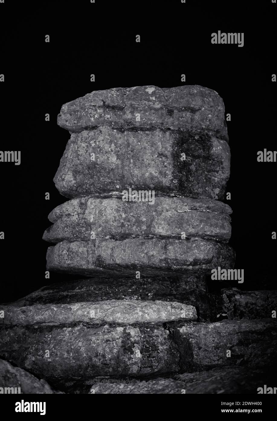 A vertical shot of huge stones on top of each other on black background ...