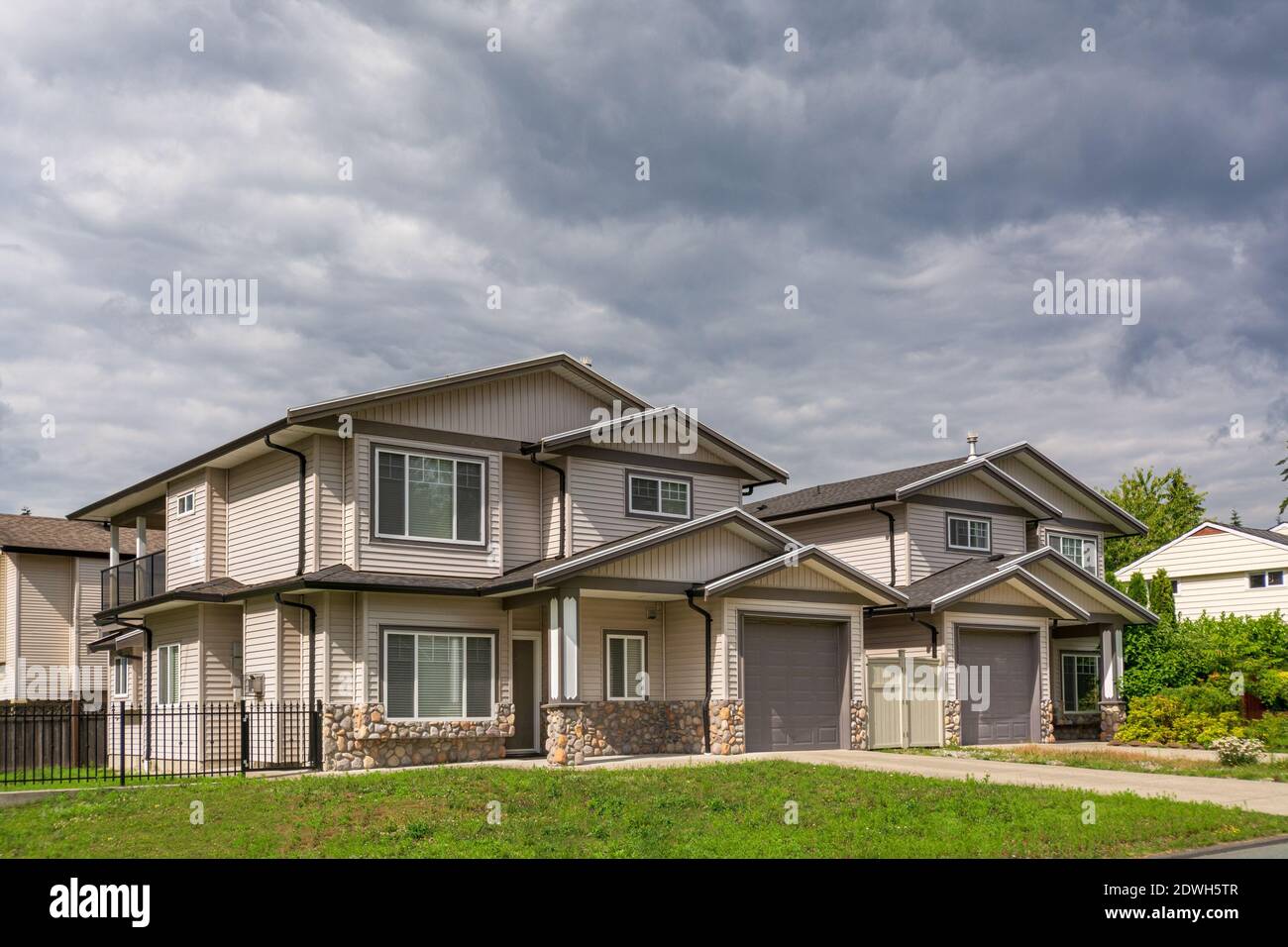 Residential duplex building with concrete driveway and green lawn in ...